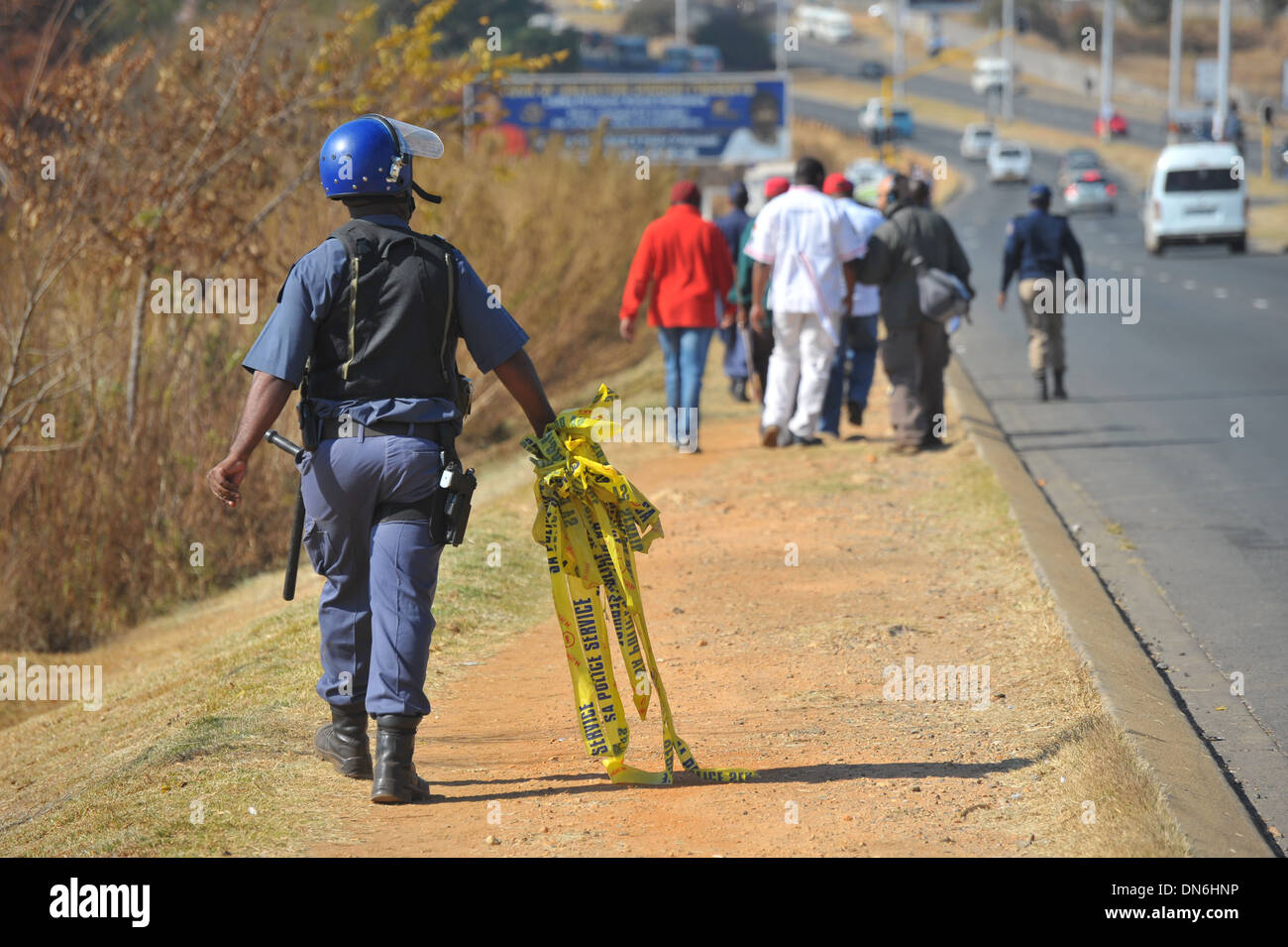 A South African JMPD police officer in riot gear holding police tape ...