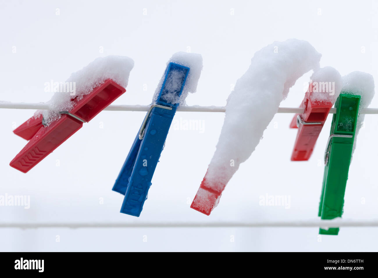 Colorful clips for washing laundry covered with snow on strip rope ...