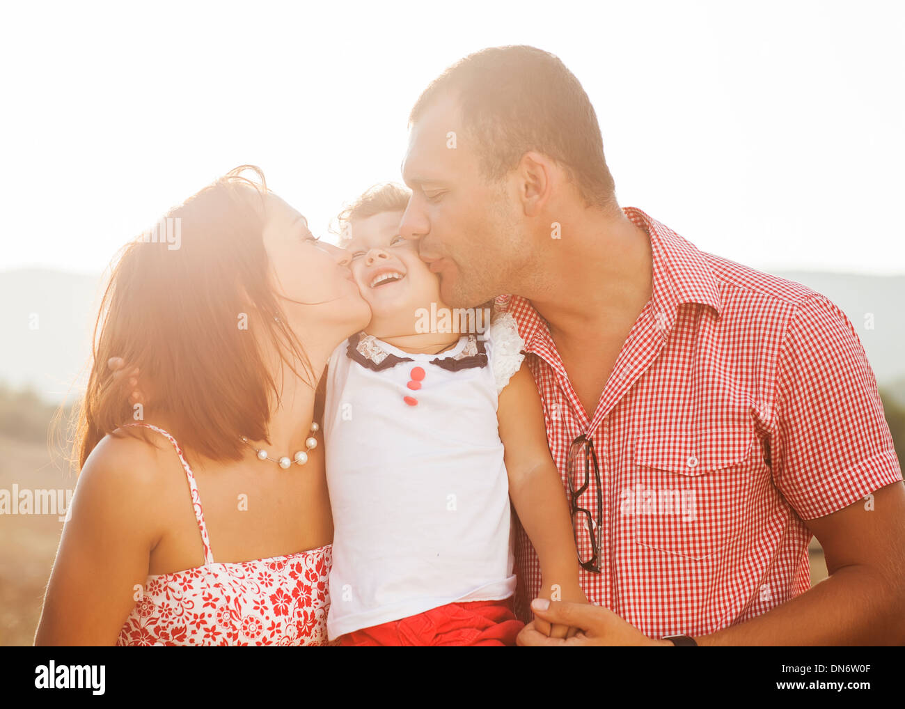 Happy mother, father and daughter in sunset Stock Photo - Alamy