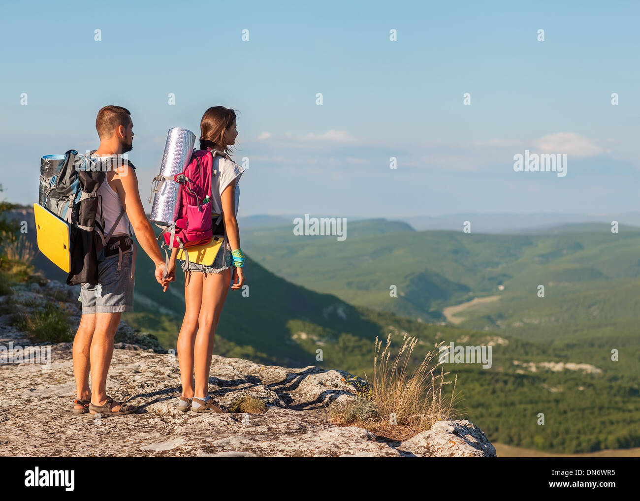 Two backpackers in mountains. Young couple examining the surroundings ...