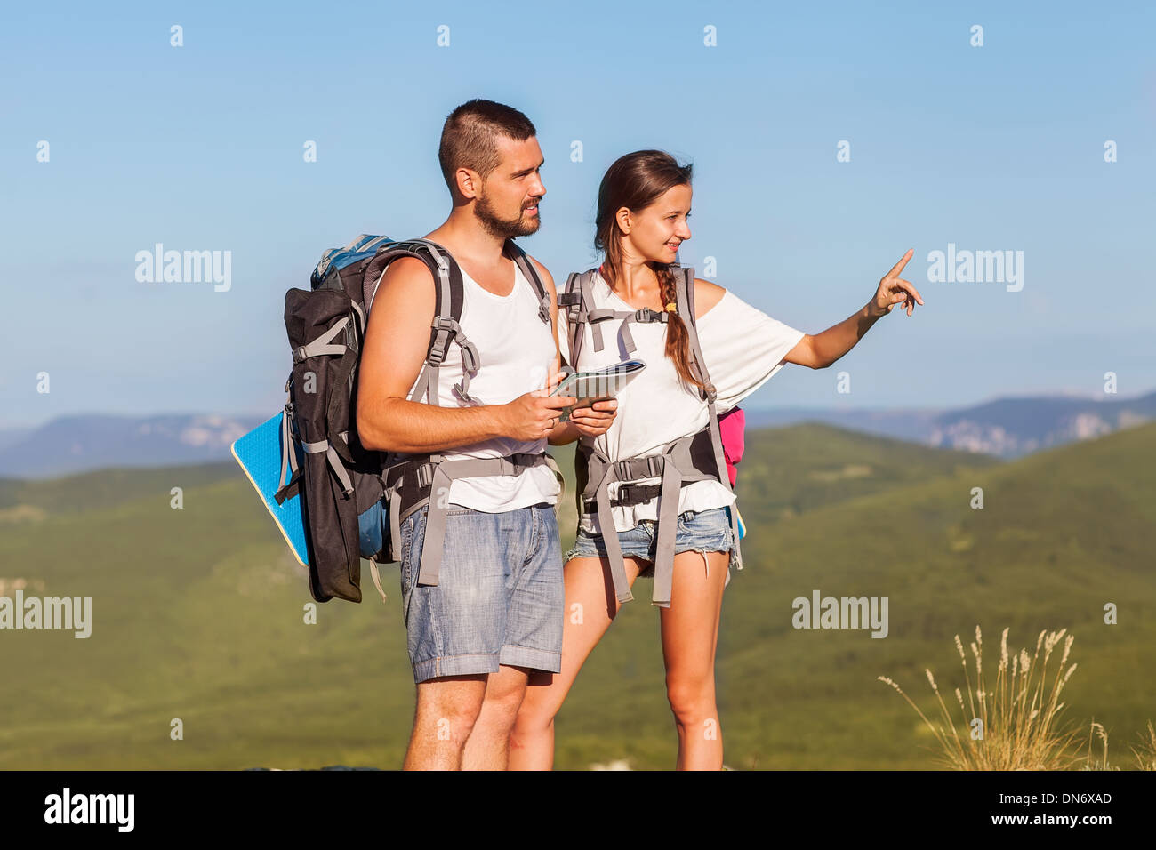 Two backpackers in mountains. Young couple examining the surroundings ...