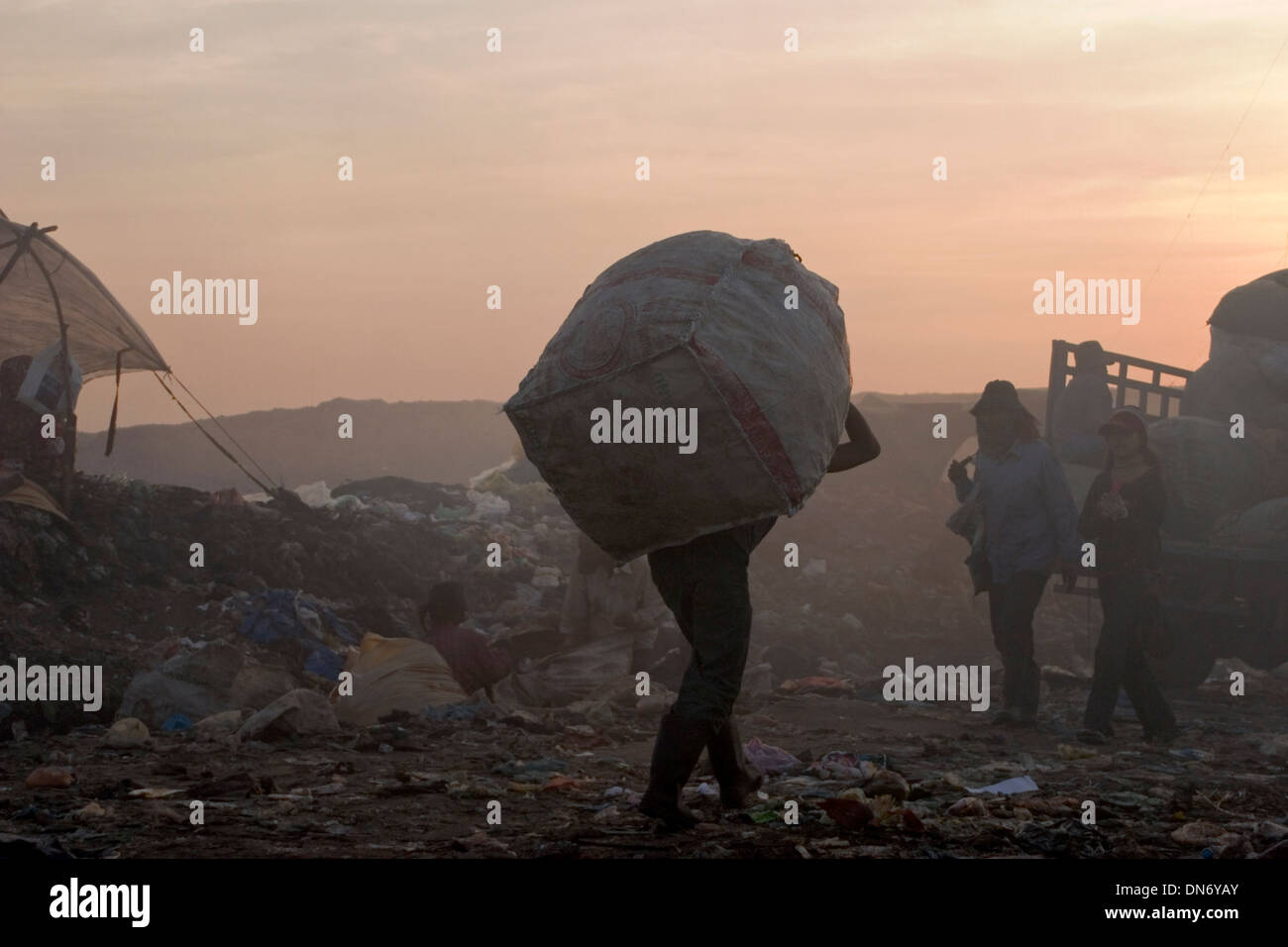 A scavenger is carrying a large sack filled with recyclable material at ...