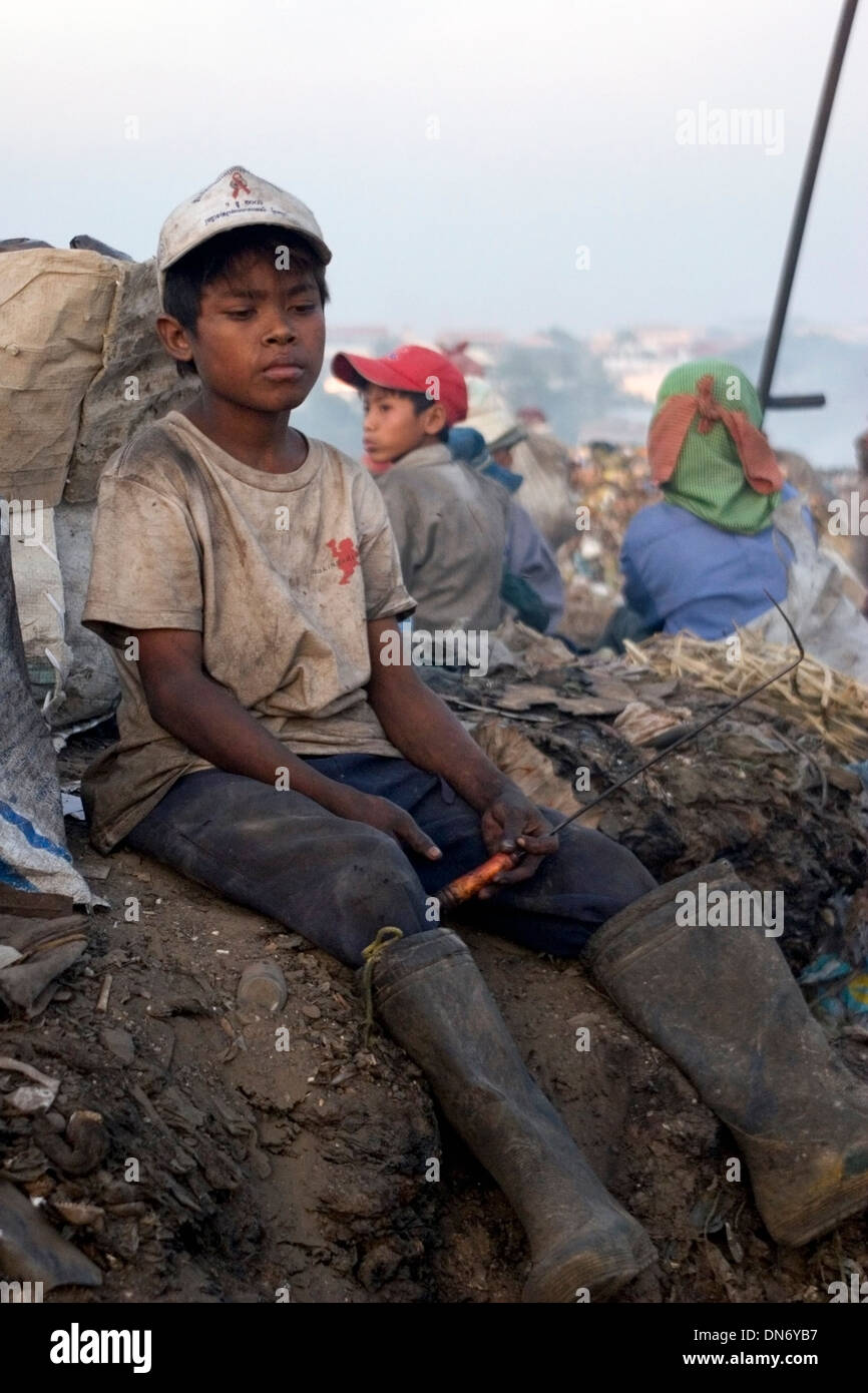 A child laborer boy who is a scavenger is sitting in the toxic and ...