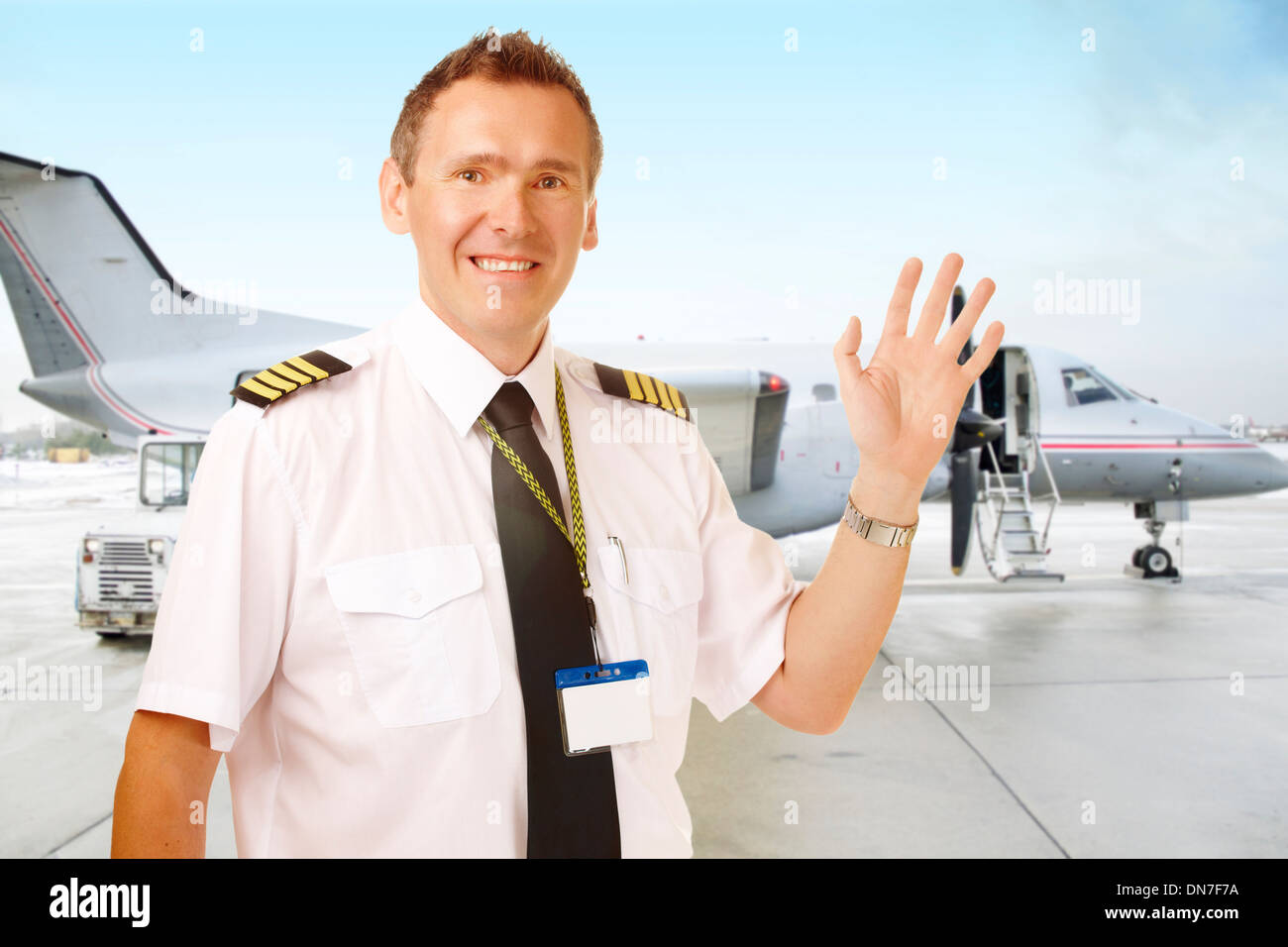Airline pilot wearing uniform with epaulettes waving, with passenger ...