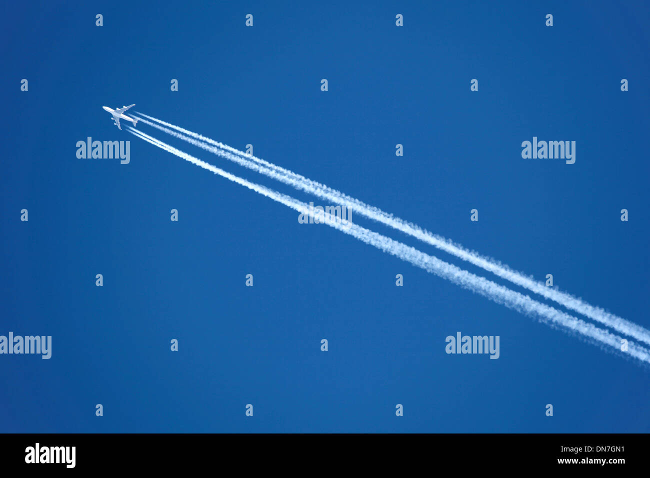 An Airplane with contrail high in the sky Stock Photo - Alamy