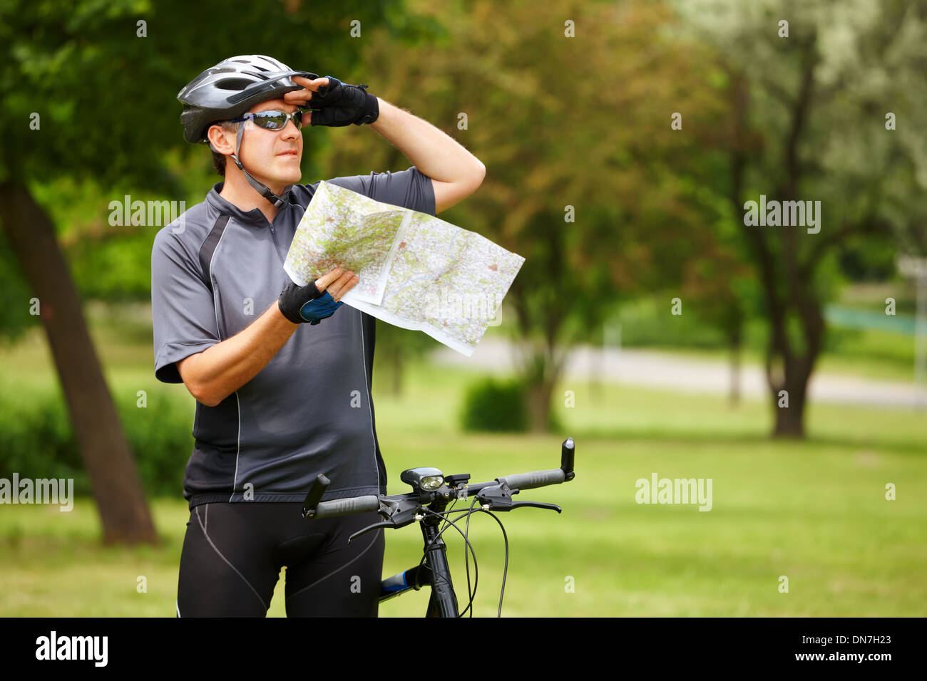 Man on bike checking map and looking around Stock Photo - Alamy