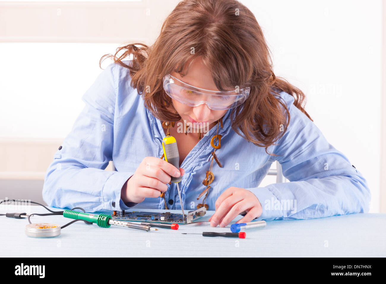 Beautiful woman in protective glasses fixing computer parts with ...
