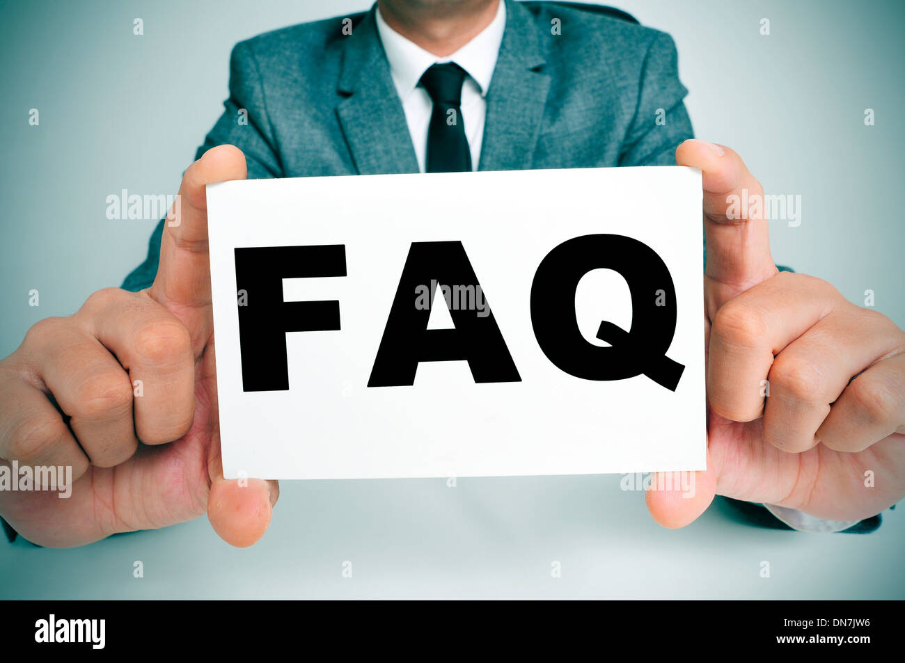a man wearing a suit sitting in a desk holding a signboard with the ...