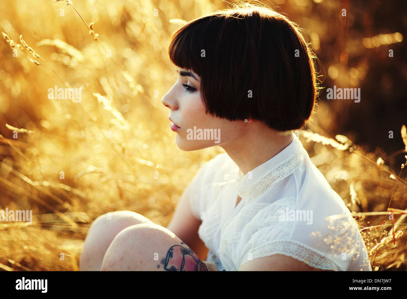 Young woman sitting on a meadow, portrait Stock Photo - Alamy