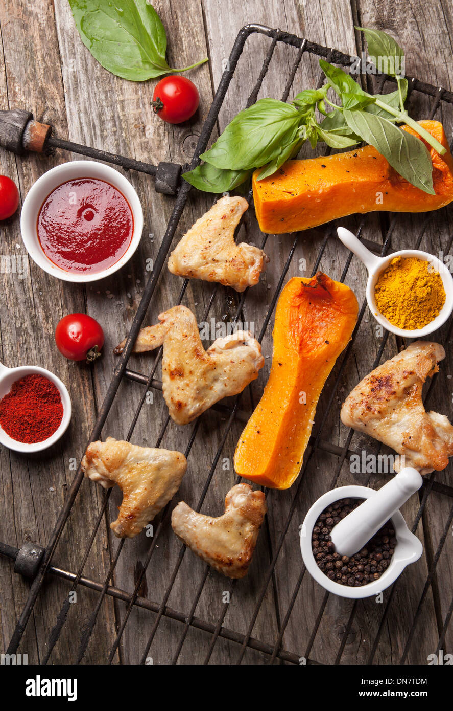 Top view on grilled chicken wings and pumpkin on old grill served with ...