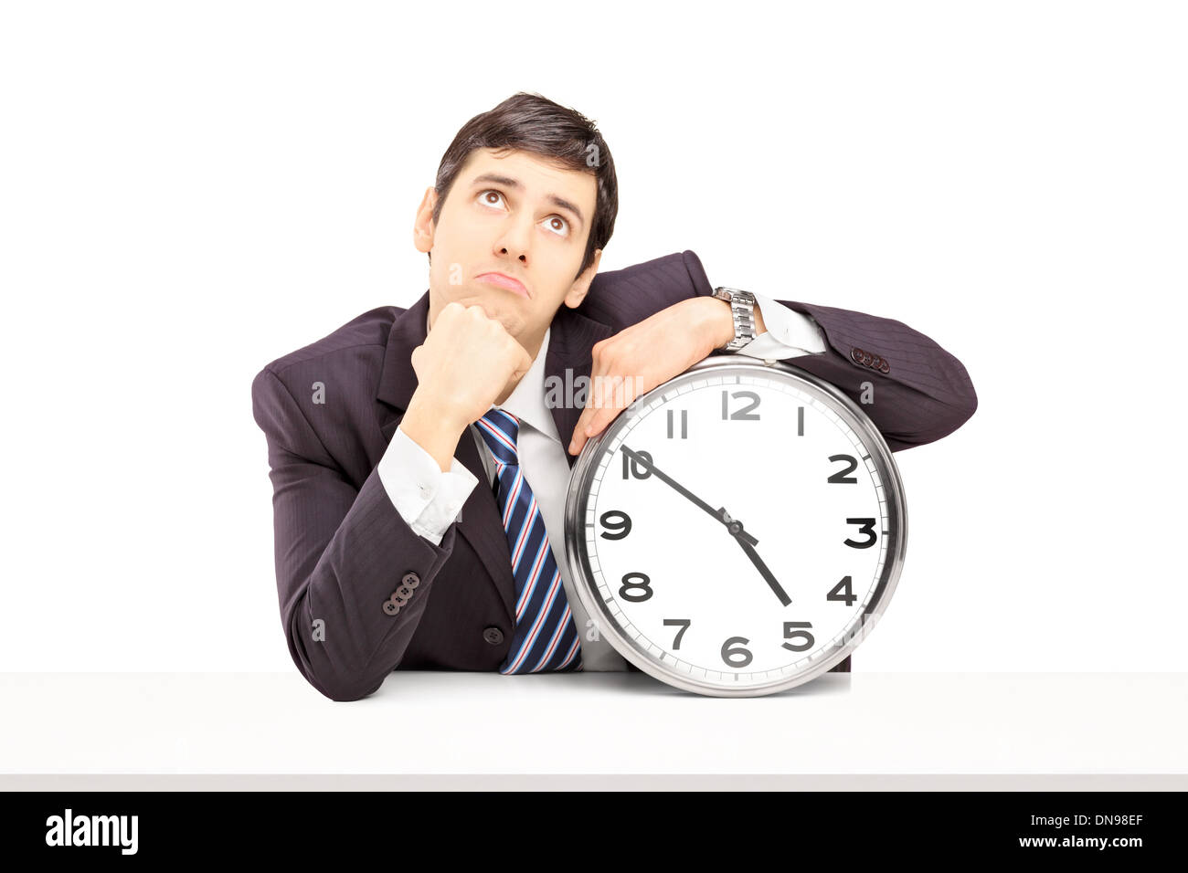 Young businessman deep in thoughts posing with a clock on a table Stock ...