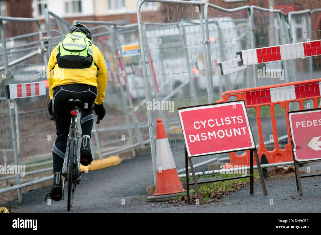 Cyclist on pavement riding past 'cyclist dismount' sign at roadworks ...