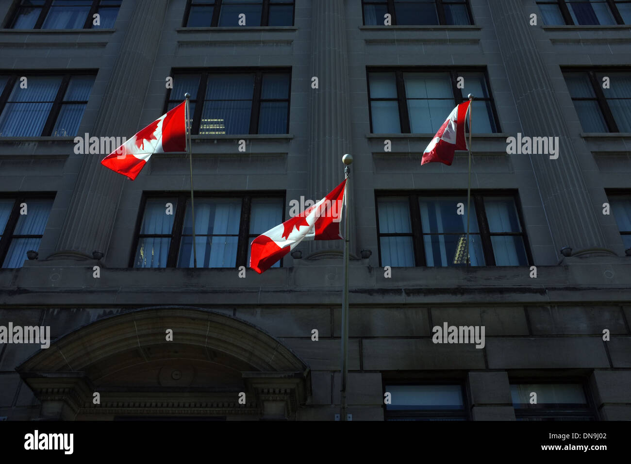 Three Canadian flags flying from the side of a government building in ...