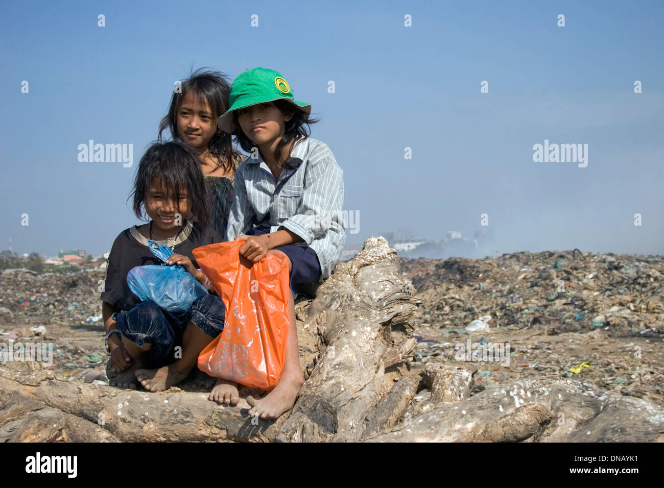 Three young child laborer girls are resting in a toxic garbage dump at ...