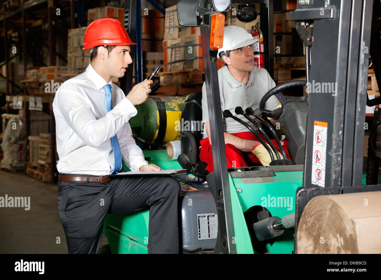 Supervisor With Clipboard Instructing Forklift Driver Stock Photo - Alamy