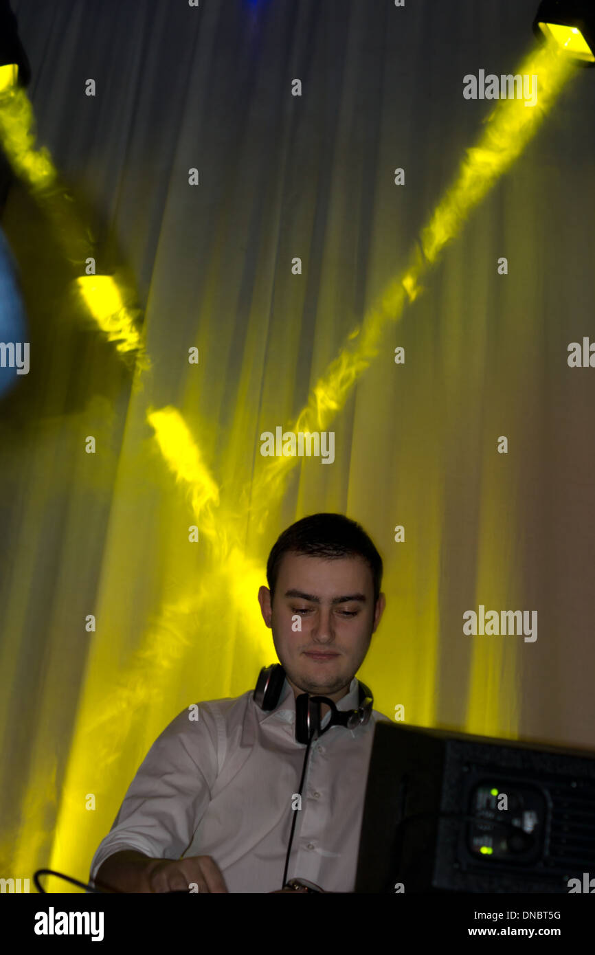 Disc jockey working under spotlights standing at his deck mixing and ...