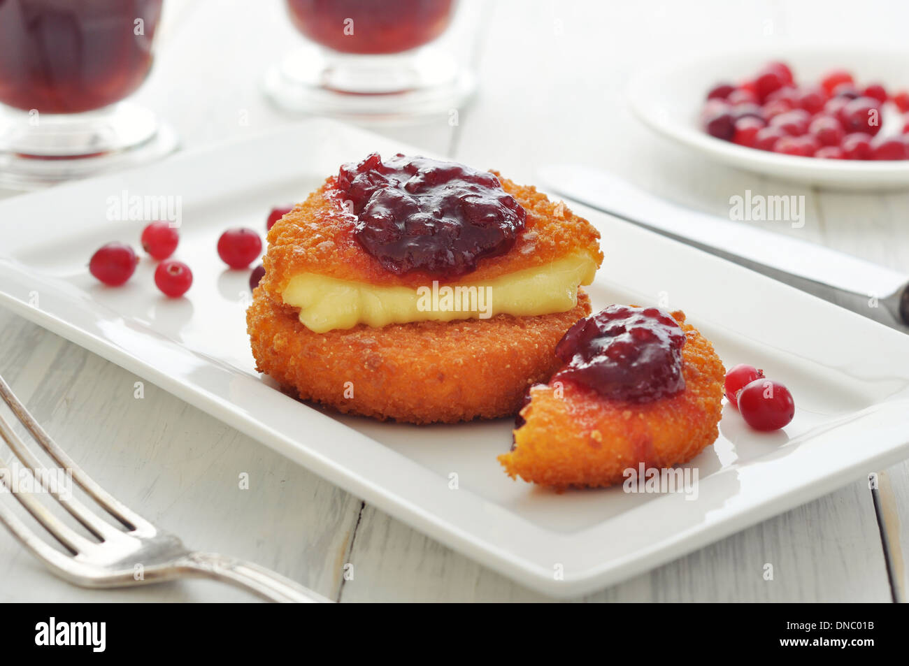 Breaded and baked camembert with cranberry sauce on white plate closeup ...
