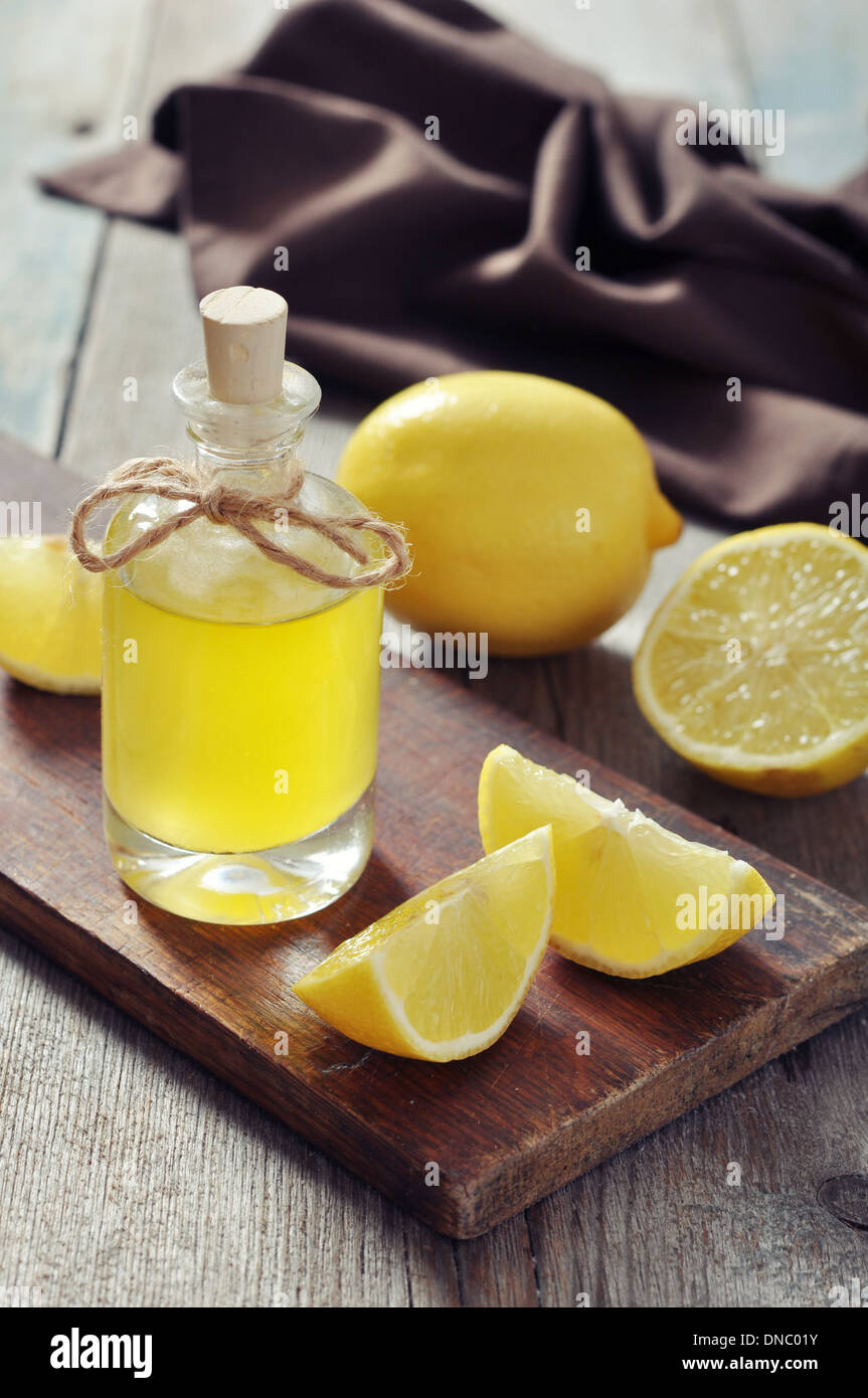 Lemon oil in a glass bottle with fresh lemon on wooden background Stock ...