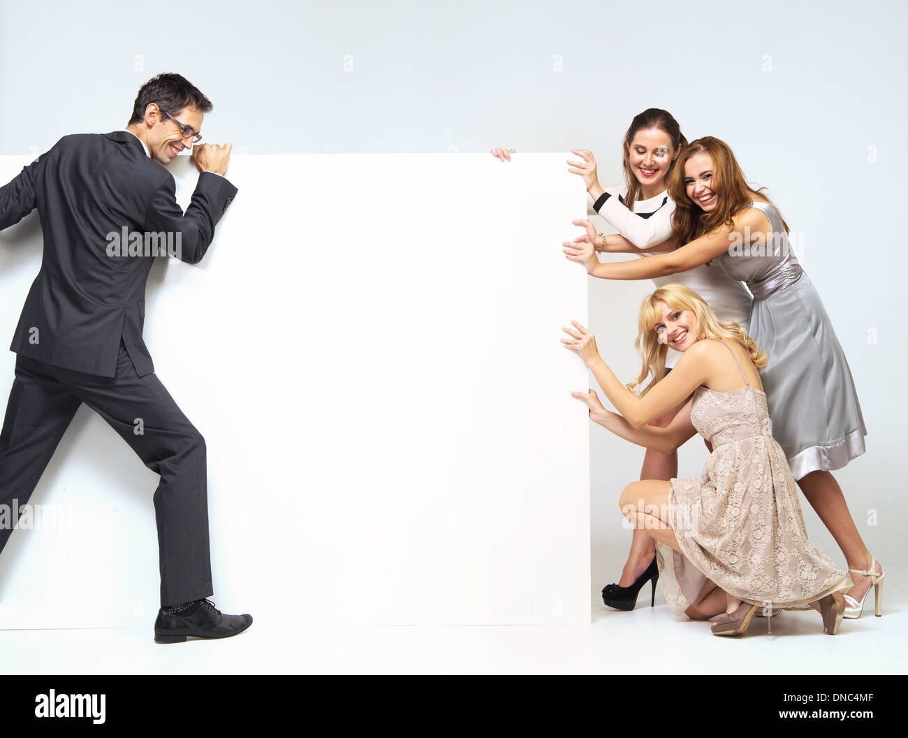 Man pushing through a board against young women Stock Photo - Alamy