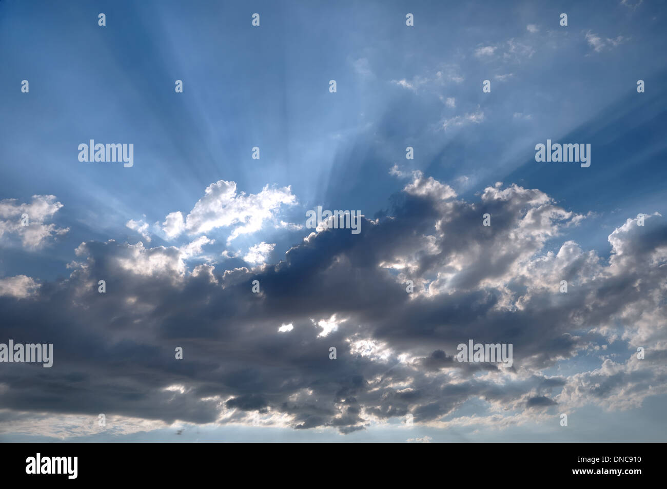 The Sun rays going through dark clouds Stock Photo - Alamy