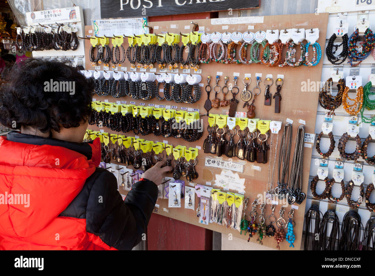 Woman shopping for Buddhist prayer beads (mala) at temple gift shop ...