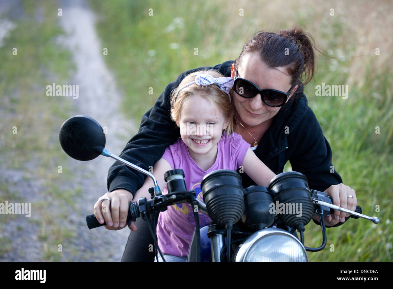 Mother riding on motorcycle with excited young daughter age 34 and 6 ...