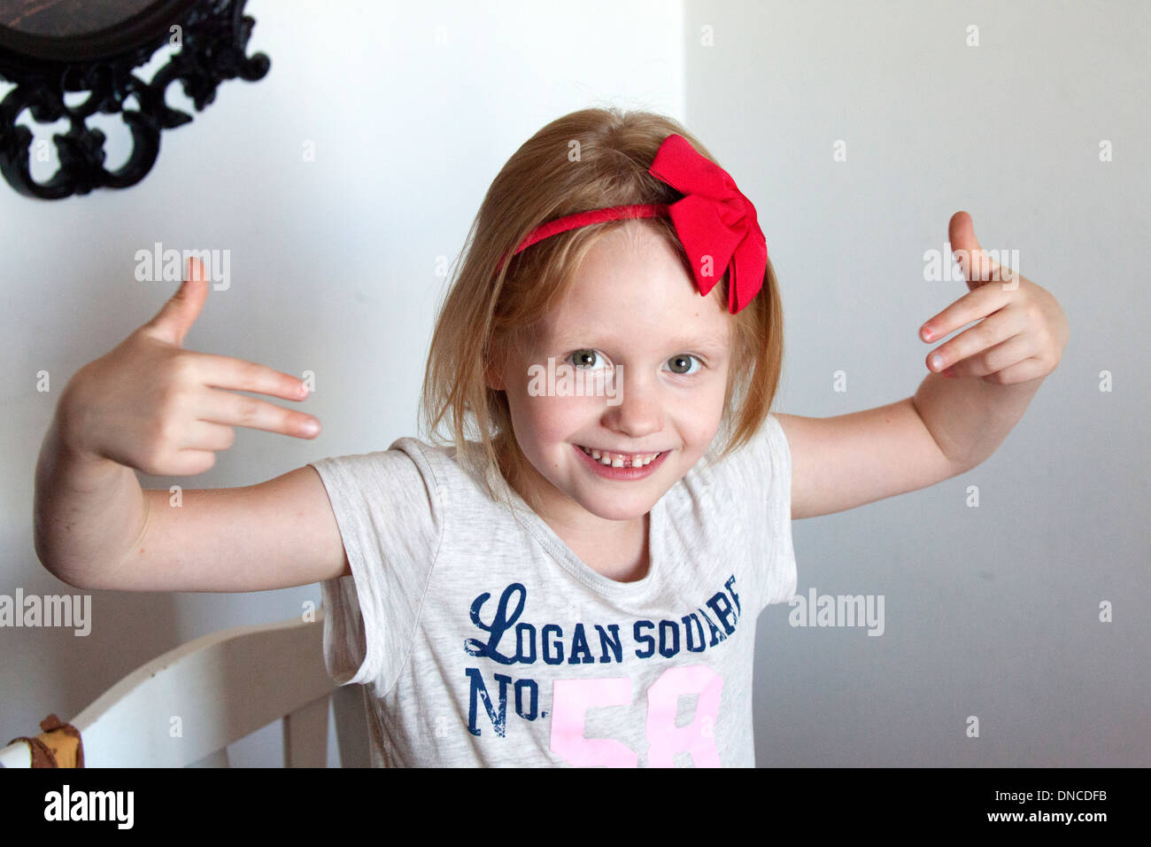 Expressive happy young girl age six giving hand signals with both arms ...