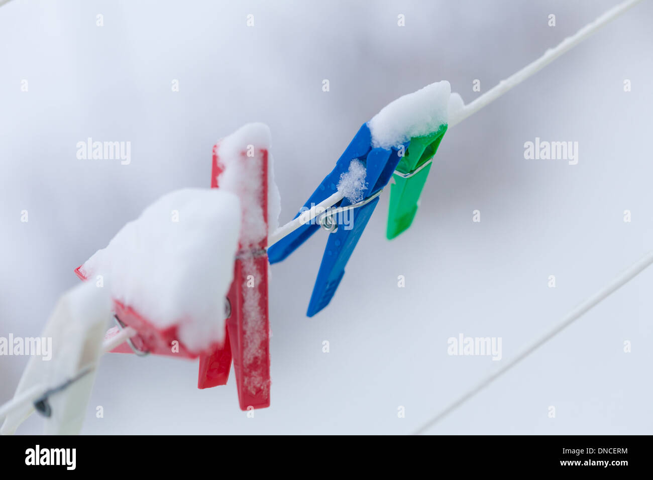 Colorful clips for washing laundry covered with snow on strip rope ...