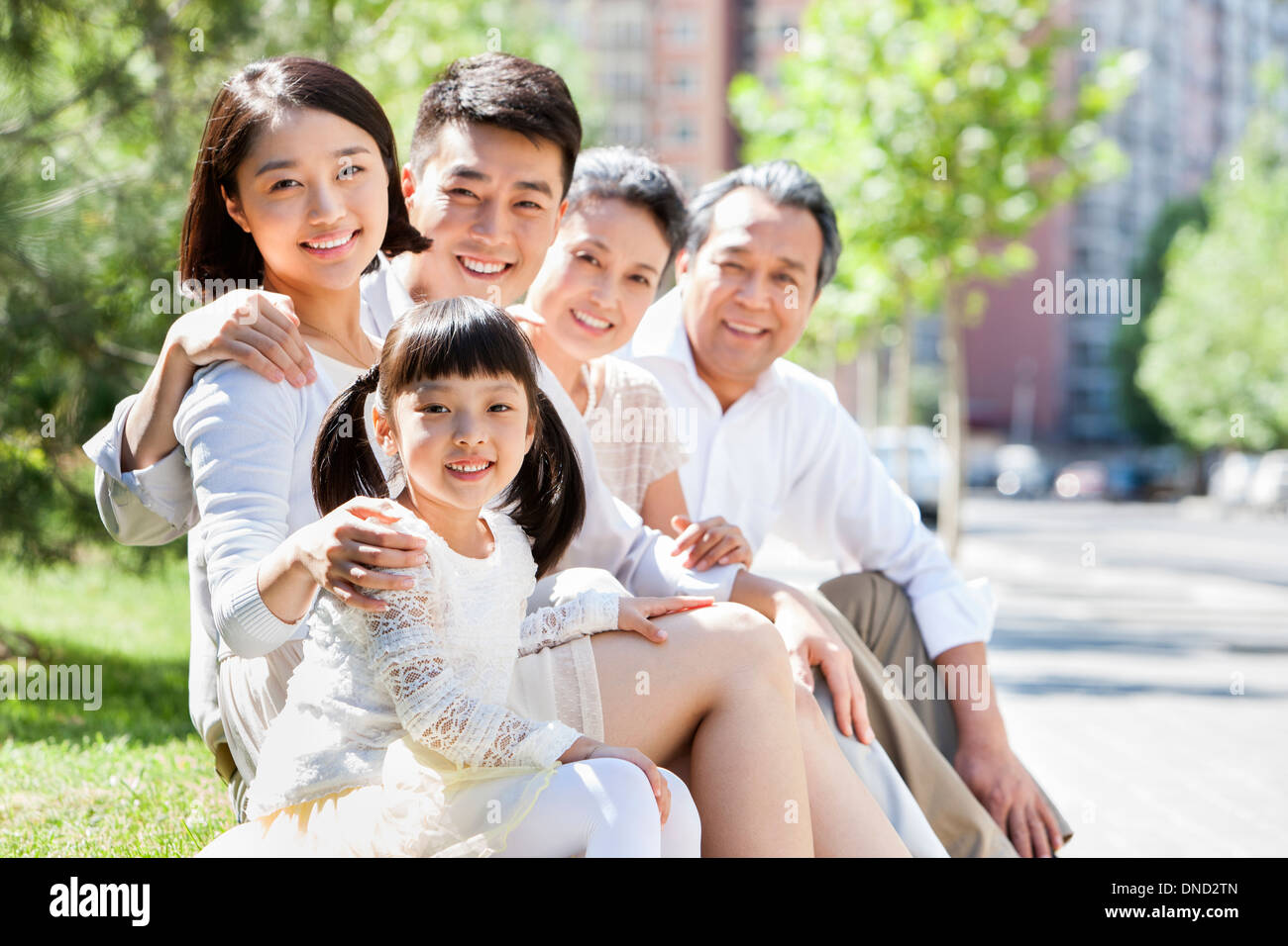 Happy family sitting in a row outdoors Stock Photo - Alamy