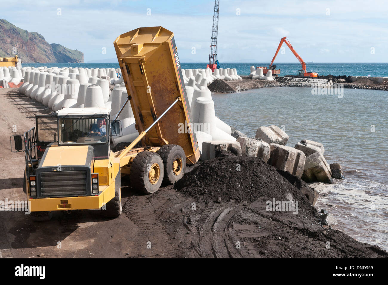 Construction lorries deposit volcanic sand form a new beach being ...