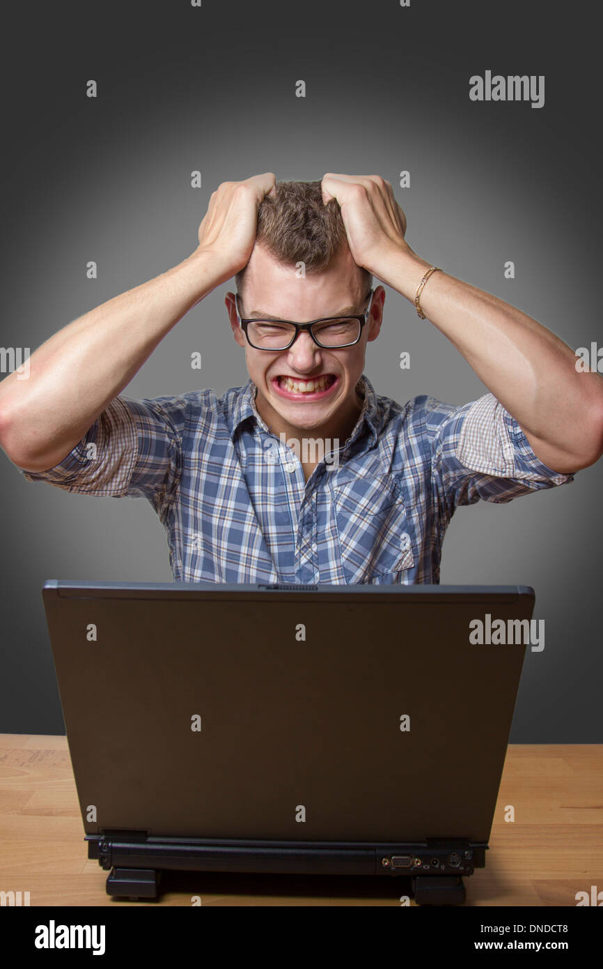 Frustrated boy is sitting at the computer and gets aggressive Stock ...