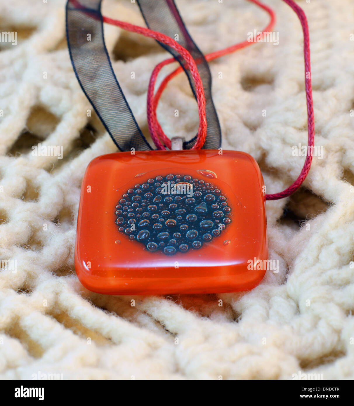 original red glass handmade amulet on knitted background Stock Photo ...