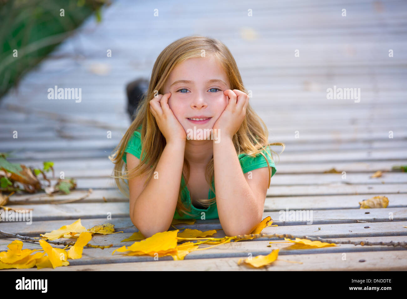 Kid girl in autumn wood deck with yellow leaves relaxed outdoor Stock ...