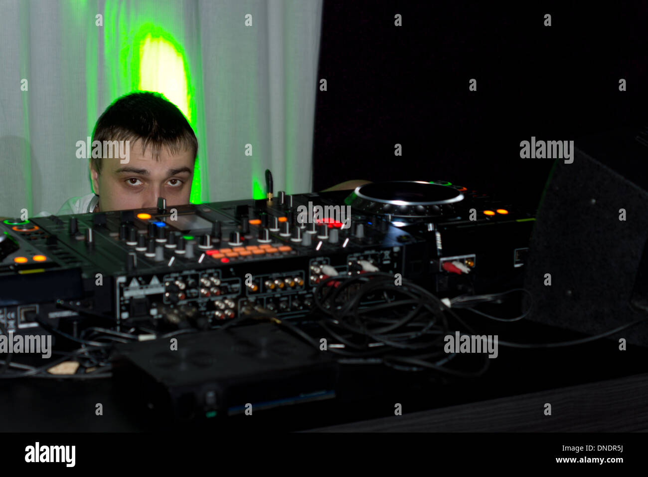 Disc jockey working at his deck as he plays music at a party with just ...