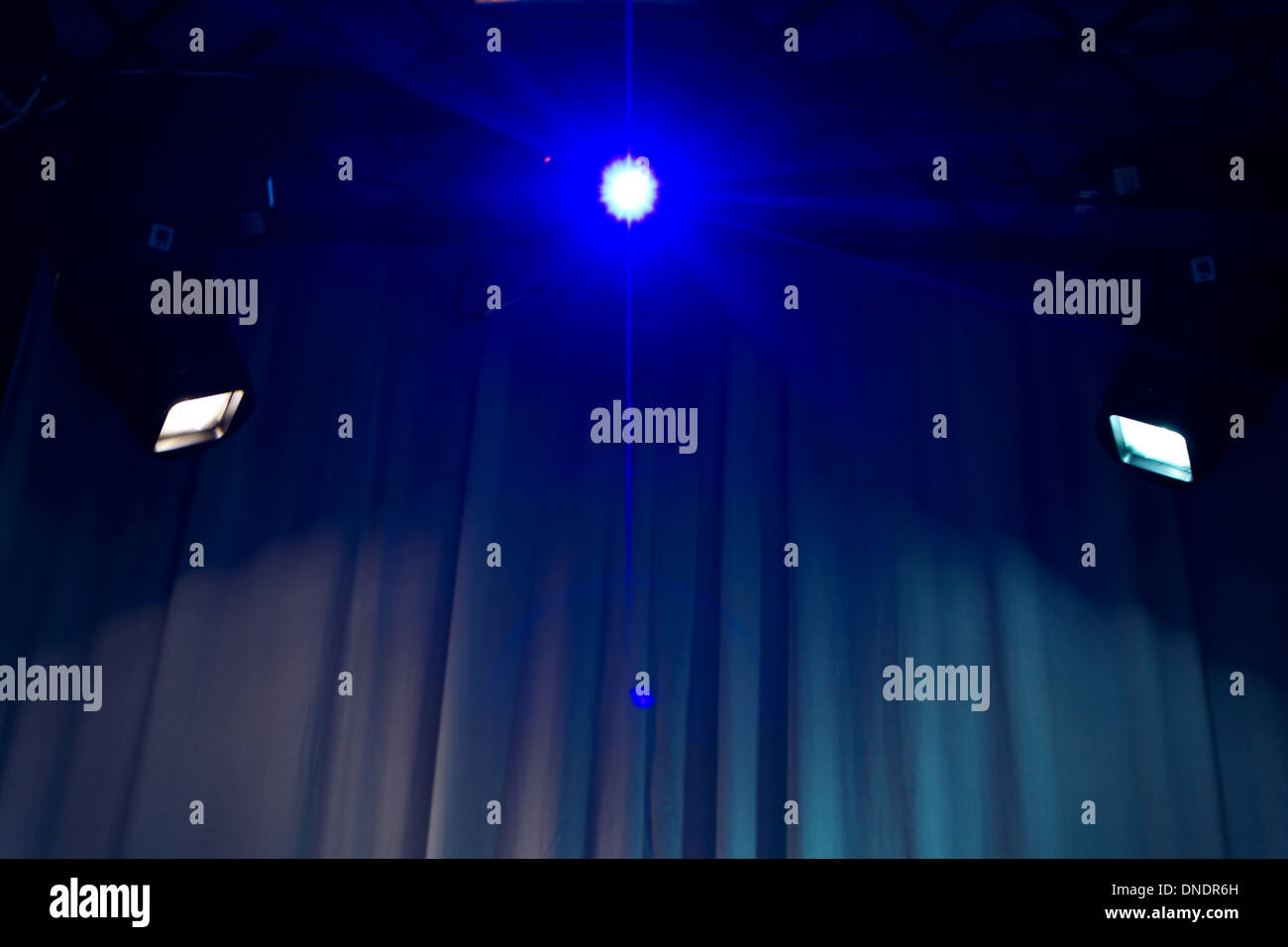 Spotlights shining on an empty venue with a white curtained backdrop ...