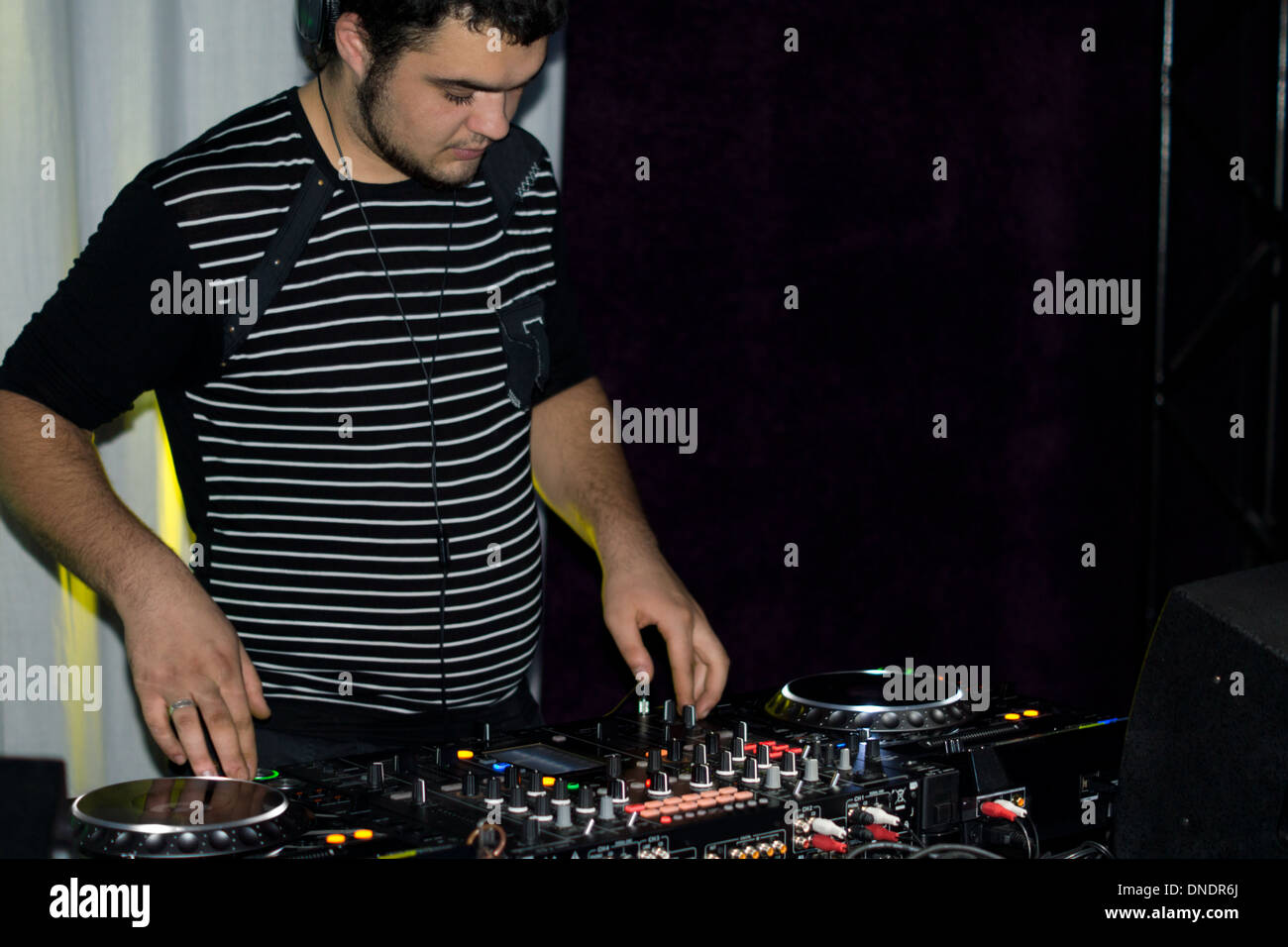 Young male disc jockey or DJ mixing music at his illuminated deck in ...