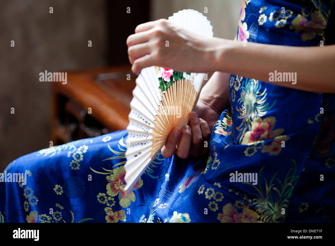 Young woman wearing cheongsam and holding folding fan Stock Photo - Alamy