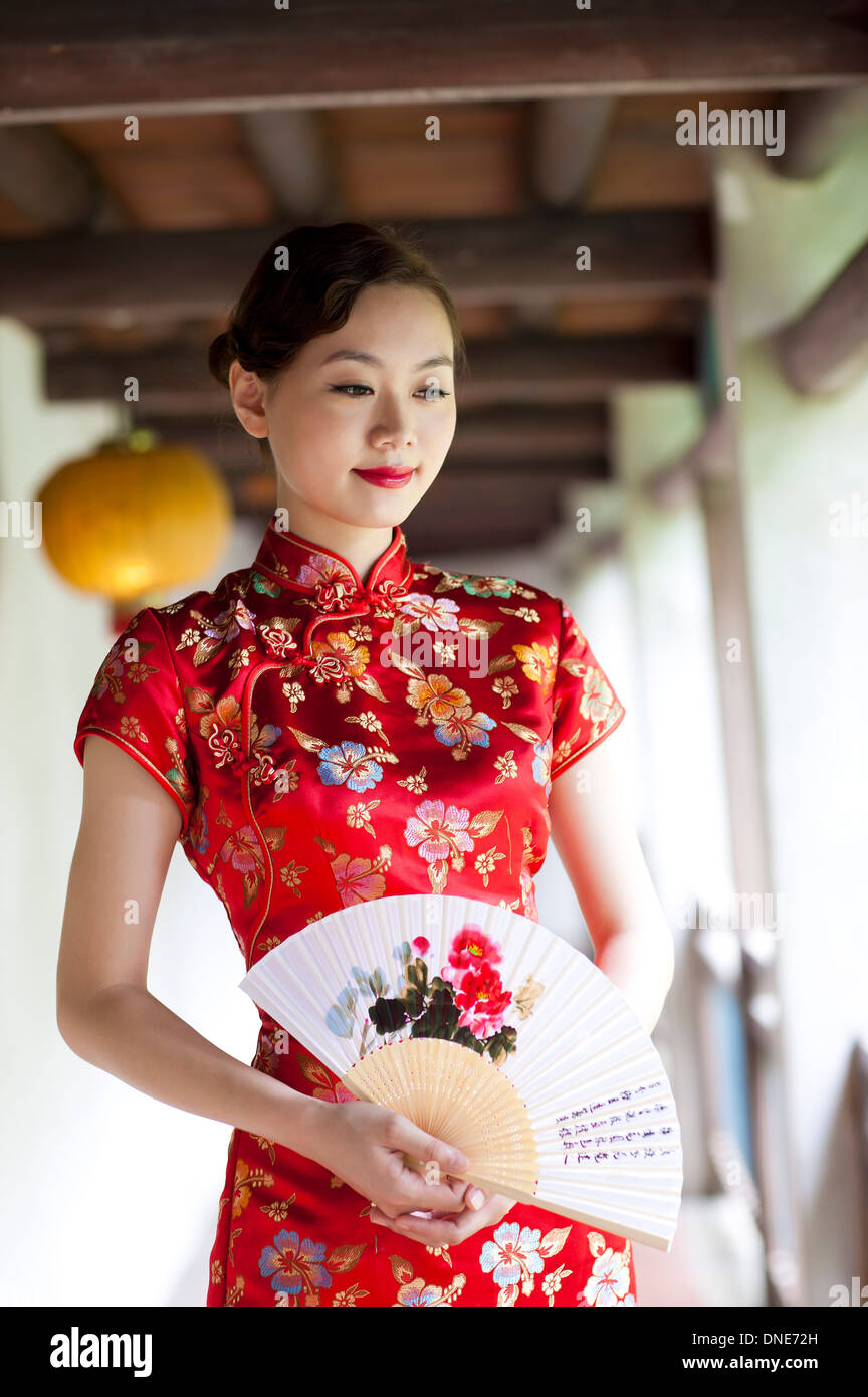 Young woman wearing cheongsam and looking down with folding fan Stock ...