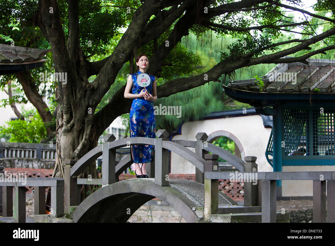 Young woman wearing cheongsam and standing with fan Stock Photo - Alamy