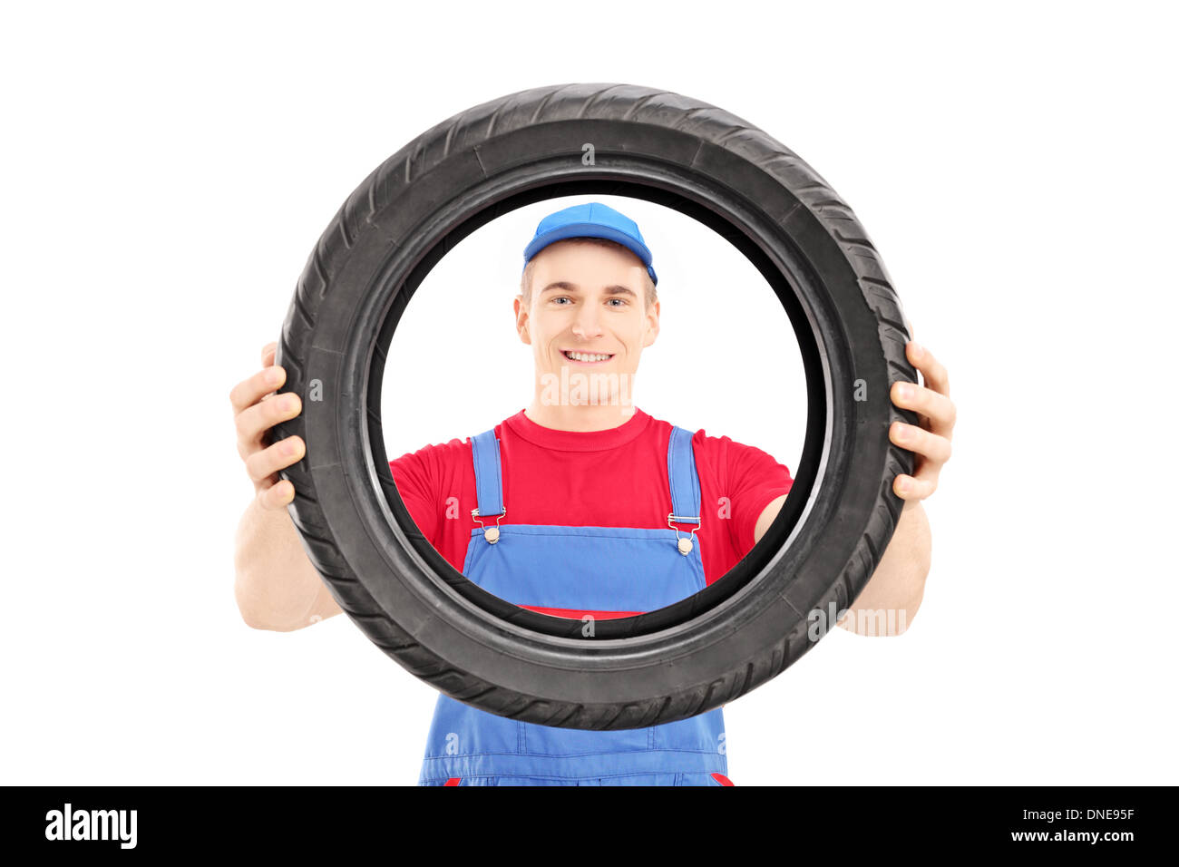 Smiling male worker holding a vehicle tire and looking at camera Stock ...