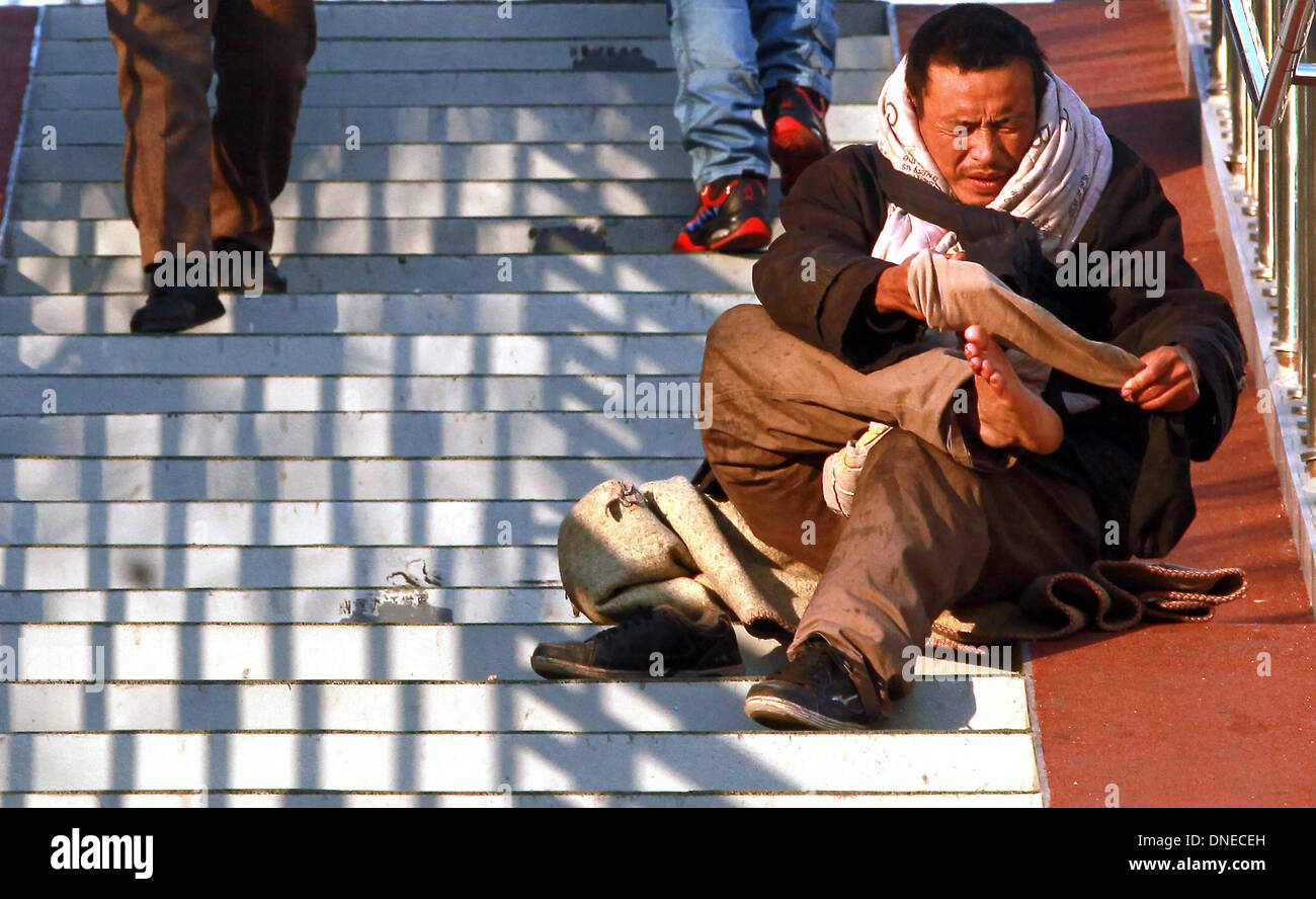 Beijing, CHINA, China. 20th Dec, 2013. A Chinese street beggar puts on ...