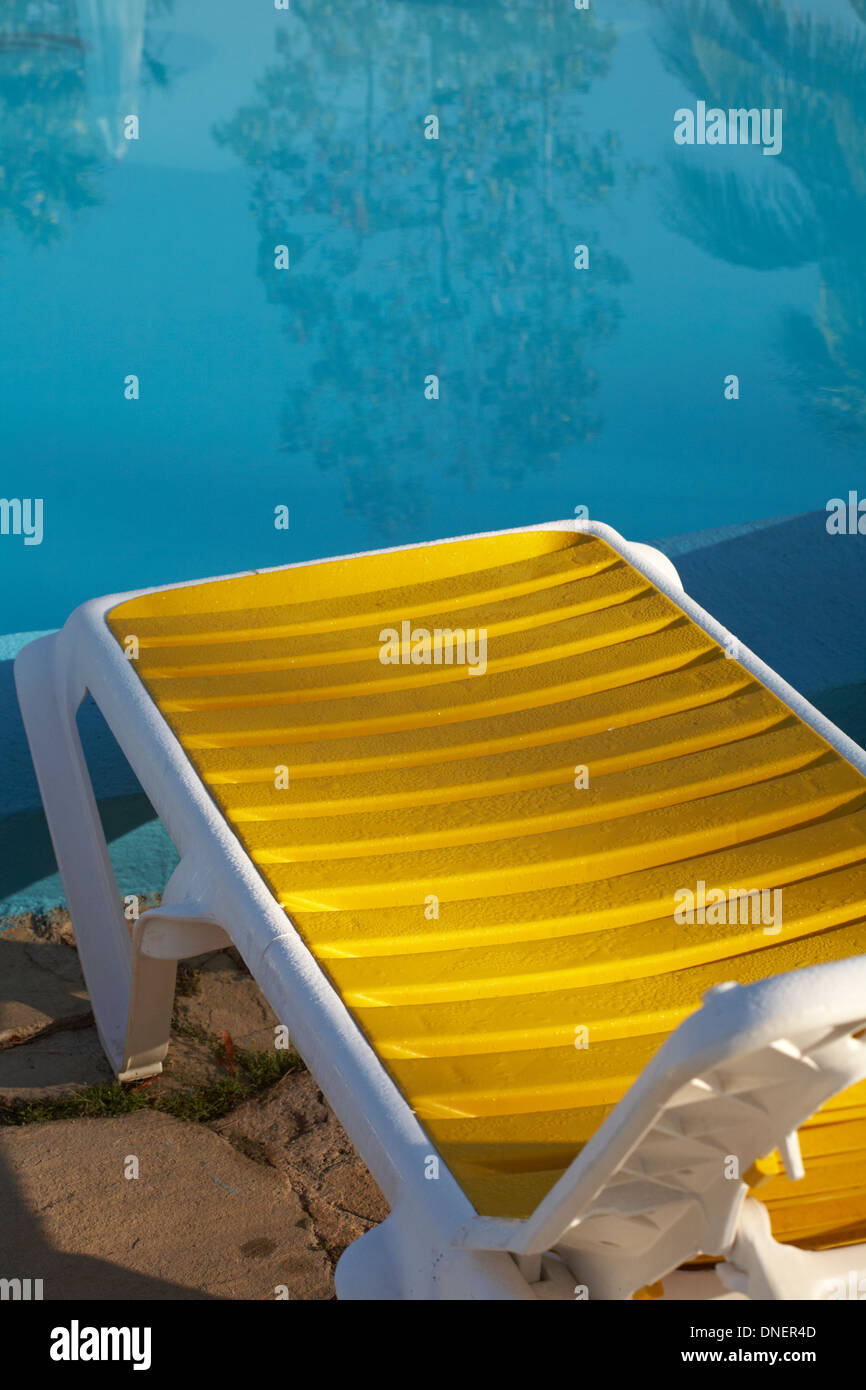 yellow sun lounger by side of swimming pool early in the morning with ...