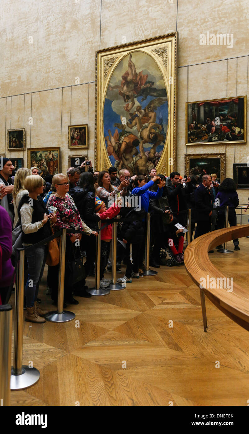 people looking and taking photos in front of the Mona Lisa painting by ...