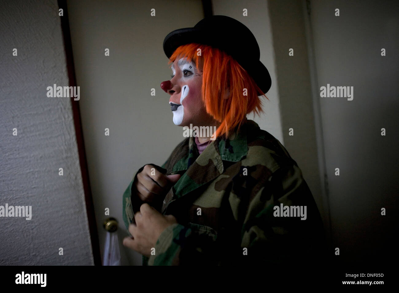 A clown puts on a military jacket as he makes up in his hotel room ...
