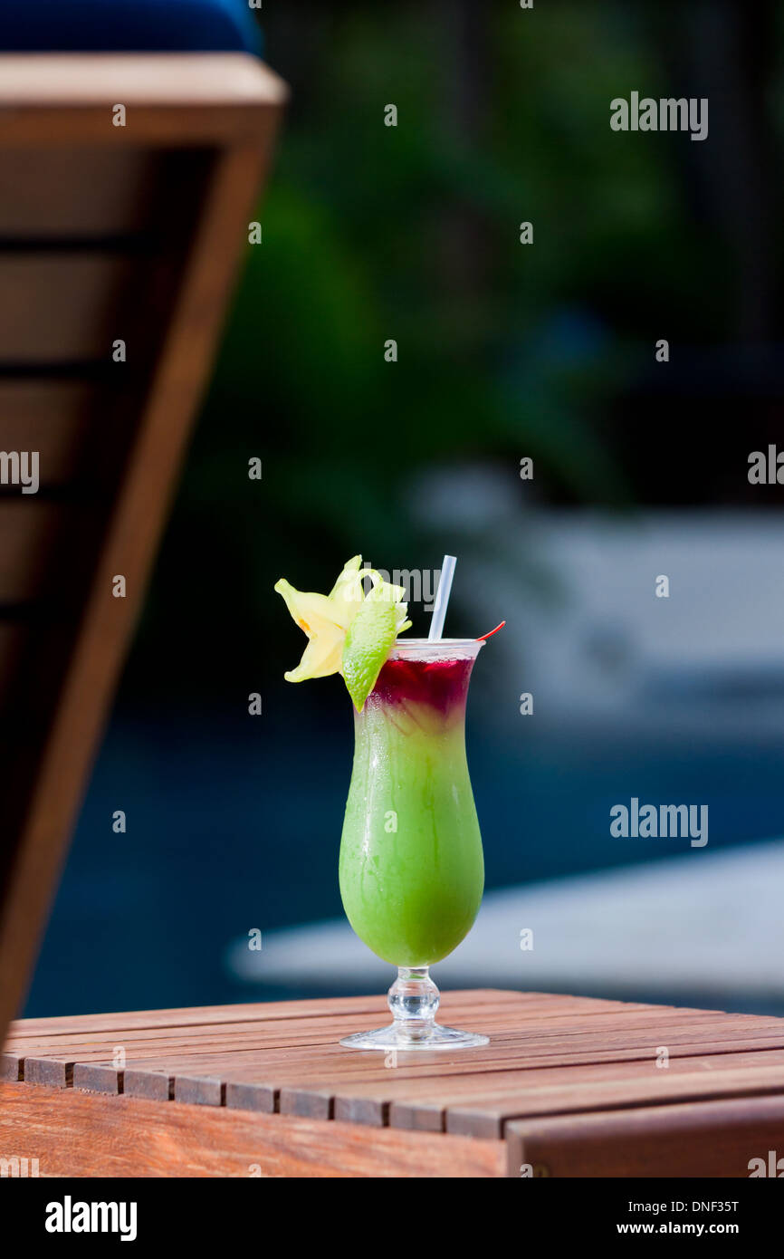 close up of a tropical cocktail served pool side in the rainforest of ...