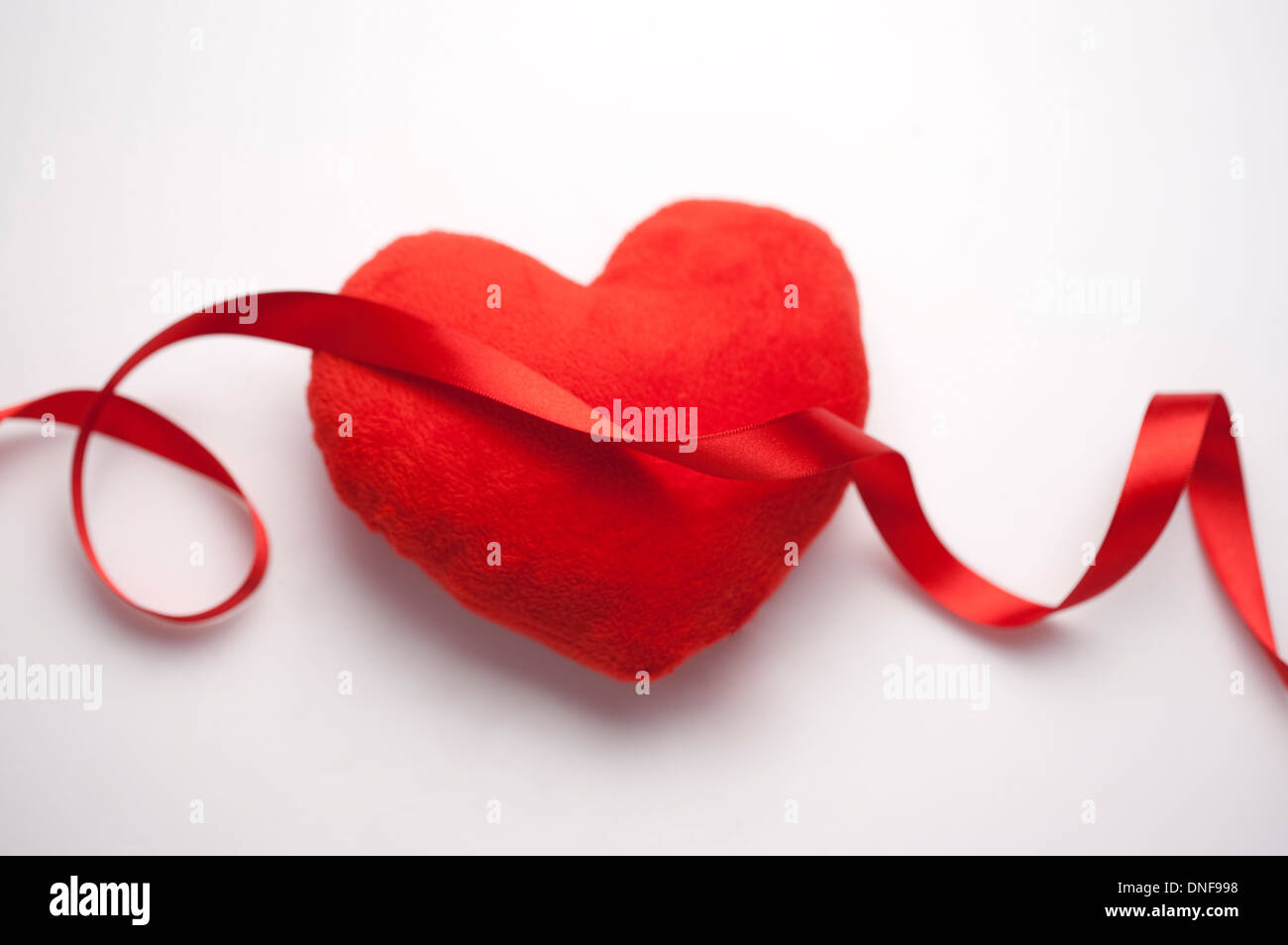 Heart shaped stuffed toy and curled red ribbon Stock Photo - Alamy