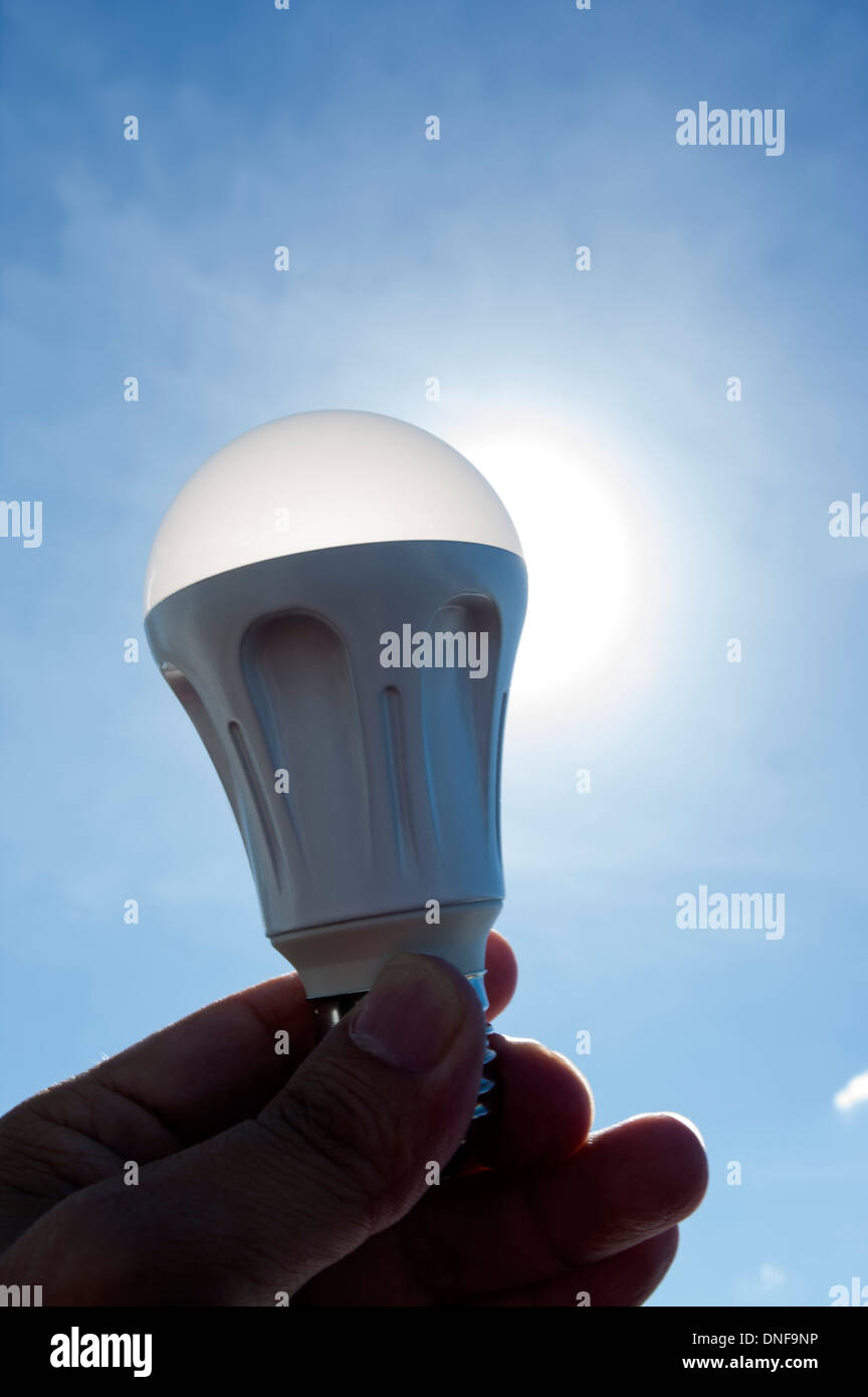 Human hand holding light bulb against the sky Stock Photo - Alamy
