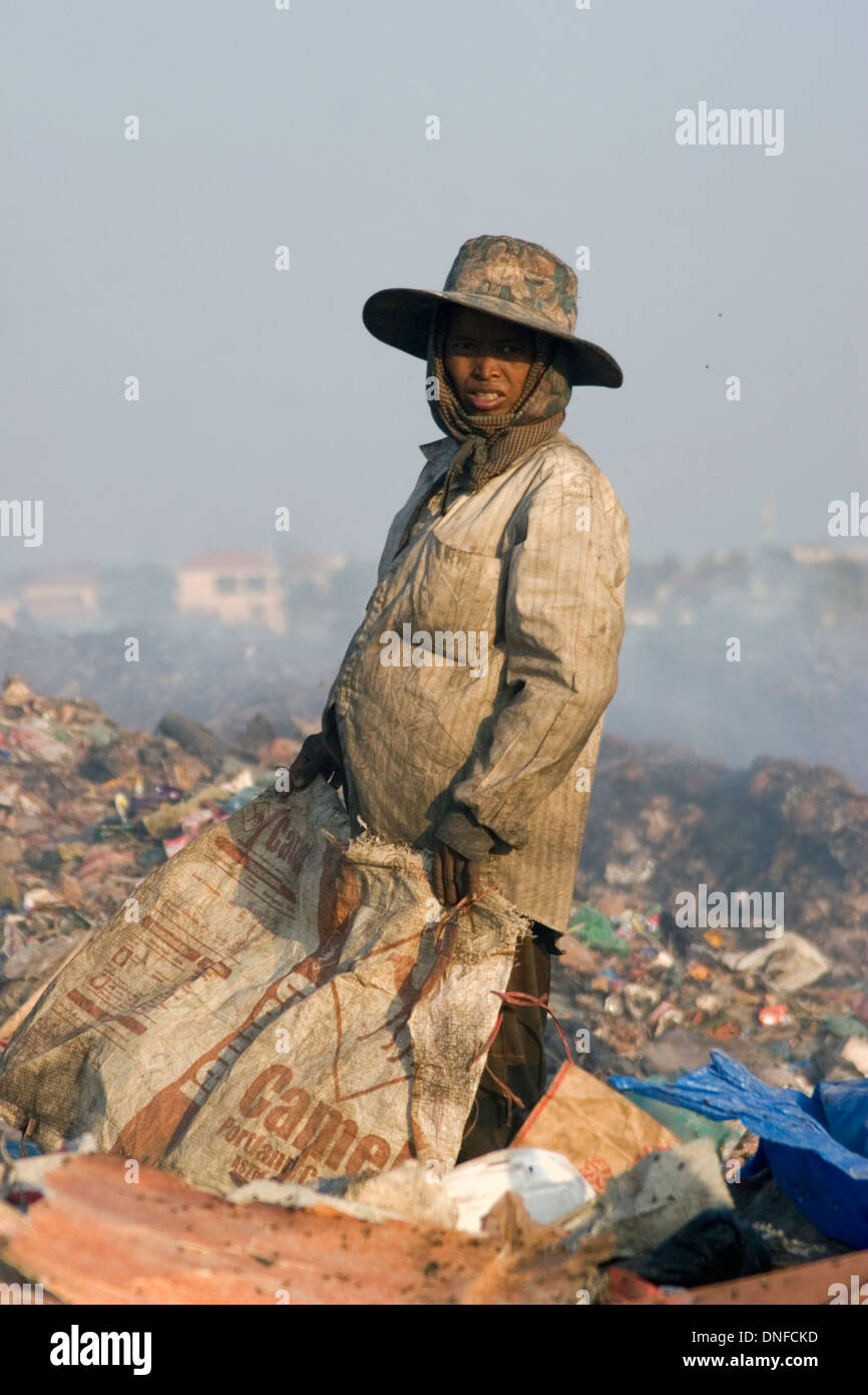A woman scavenger who collects recyclable material is looking at the ...