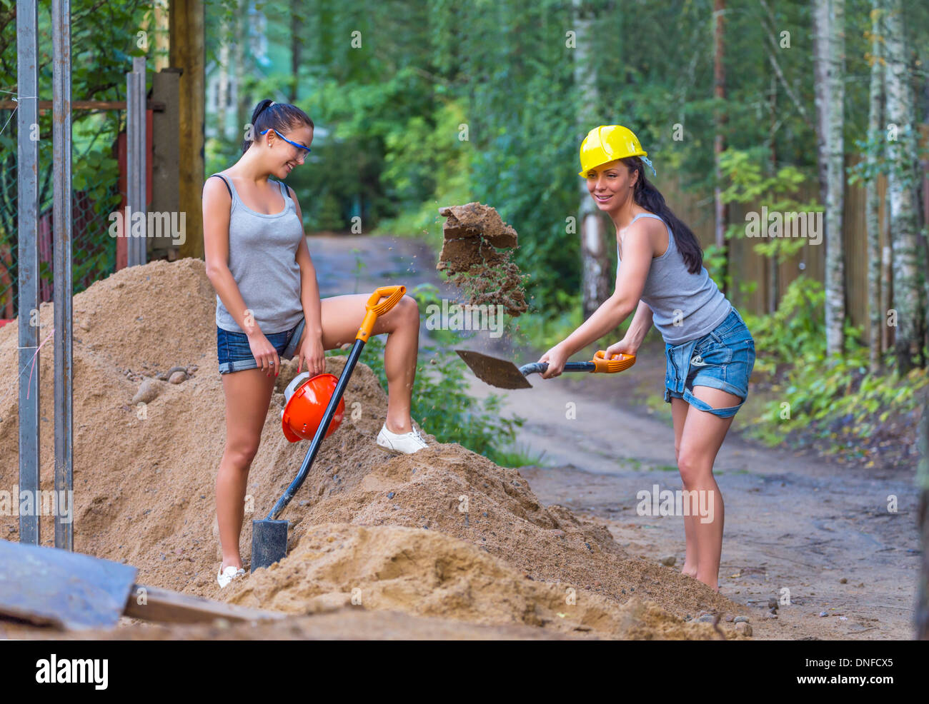Pretty young woman builder digging a shovel Stock Photo - Alamy