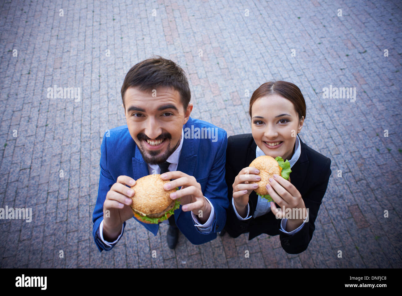 Two hungry colleagues eating sandwiches outside Stock Photo - Alamy